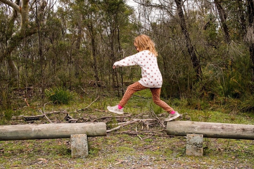 Image of Girl jumping between logs in nature reserve park - Austockphoto