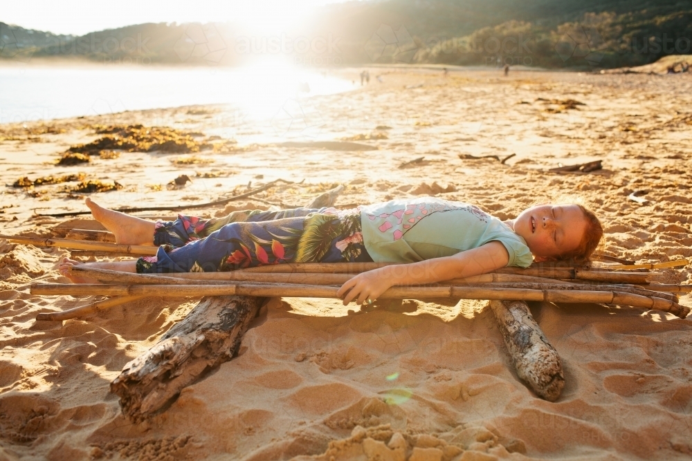 Image of Girl laying on a bamboo raft on the beach - Austockphoto
