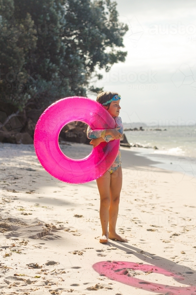 Image of Girl on the beach with a pink floater - Austockphoto