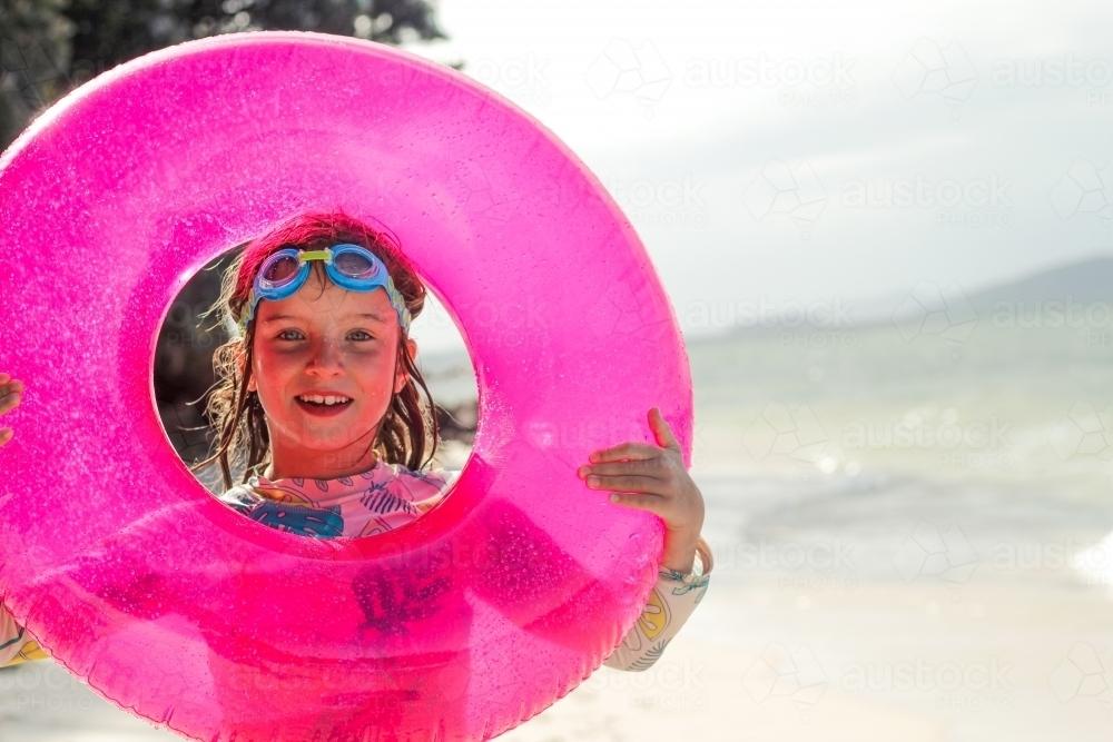 Image of Girl on the beach with a pink floater - Austockphoto
