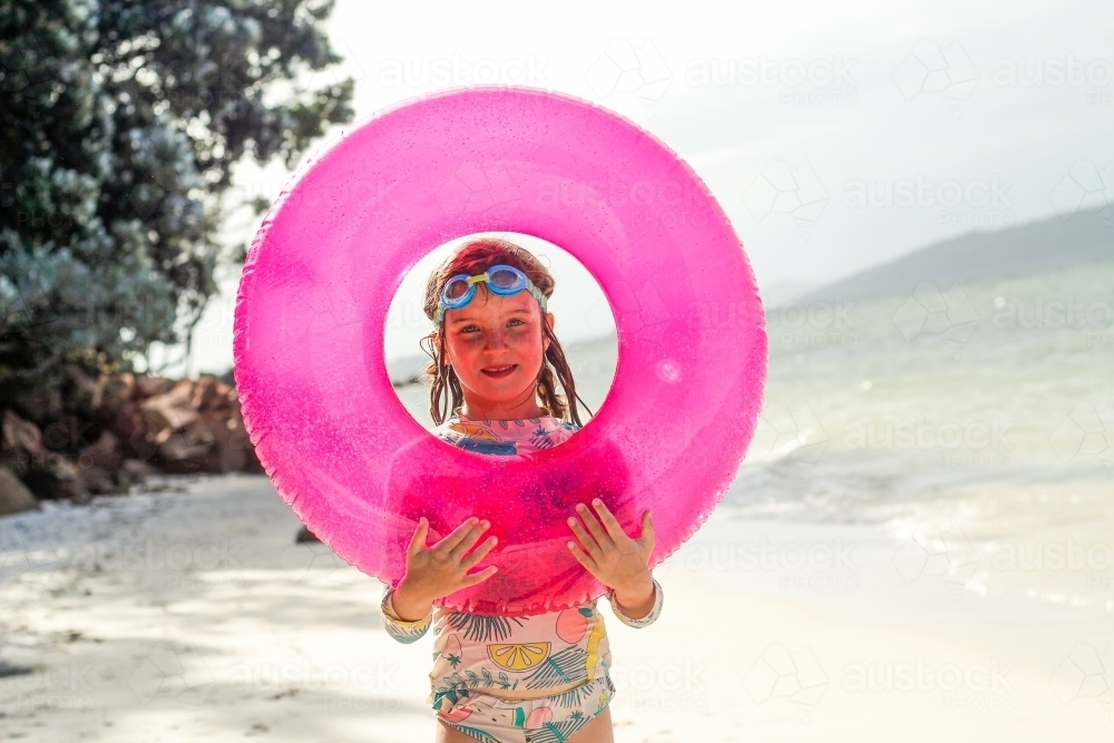 Image of Girl on the beach with a pink floater - Austockphoto