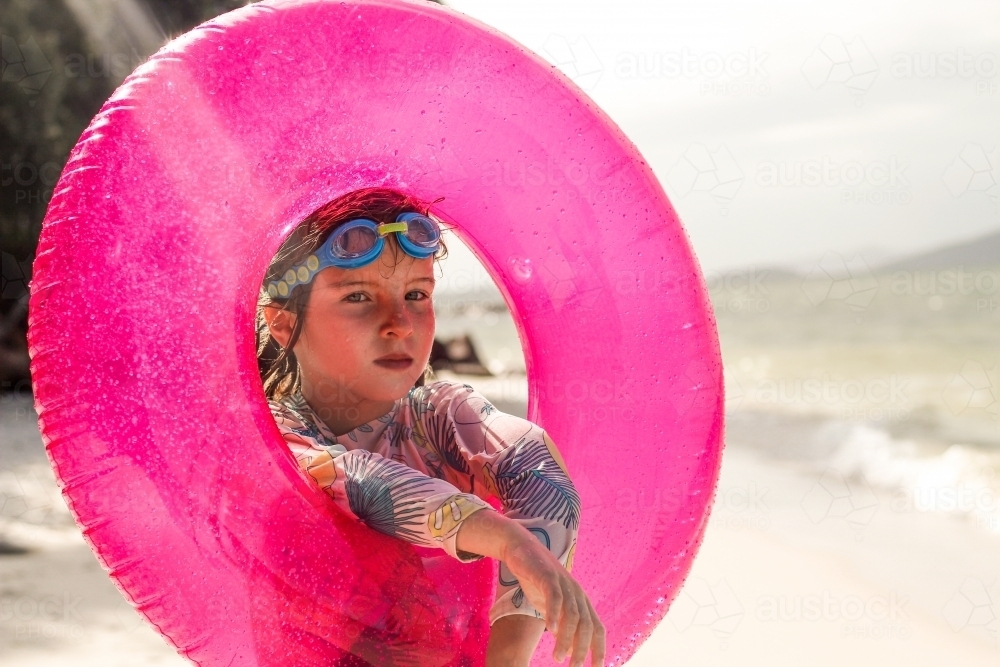 Image of Girl on the beach with a pink swim ring - Austockphoto