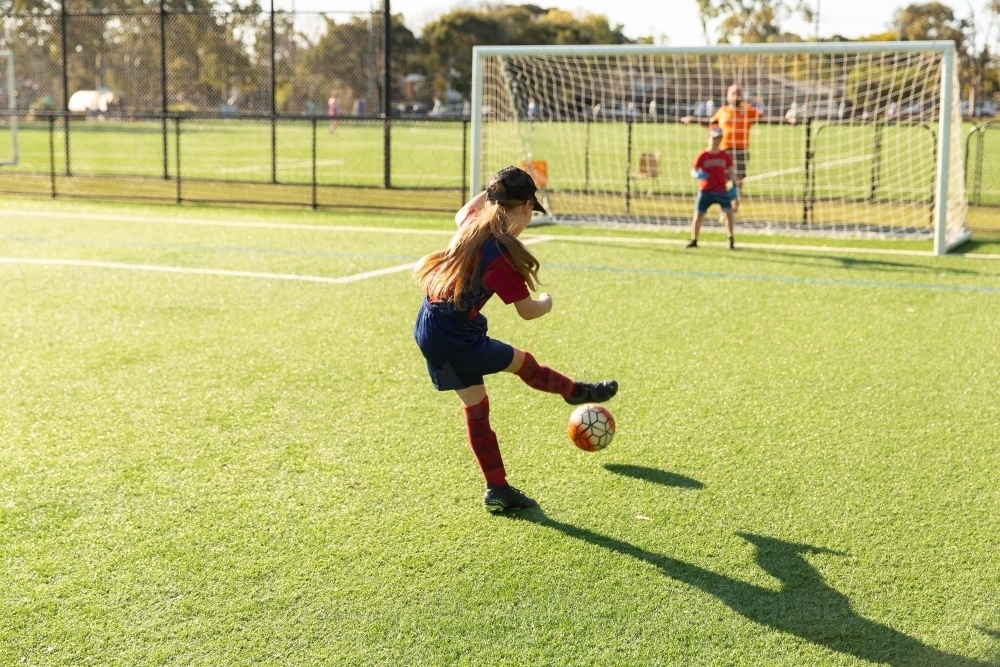 Image of girl playing soccer and kicking a goal - Austockphoto