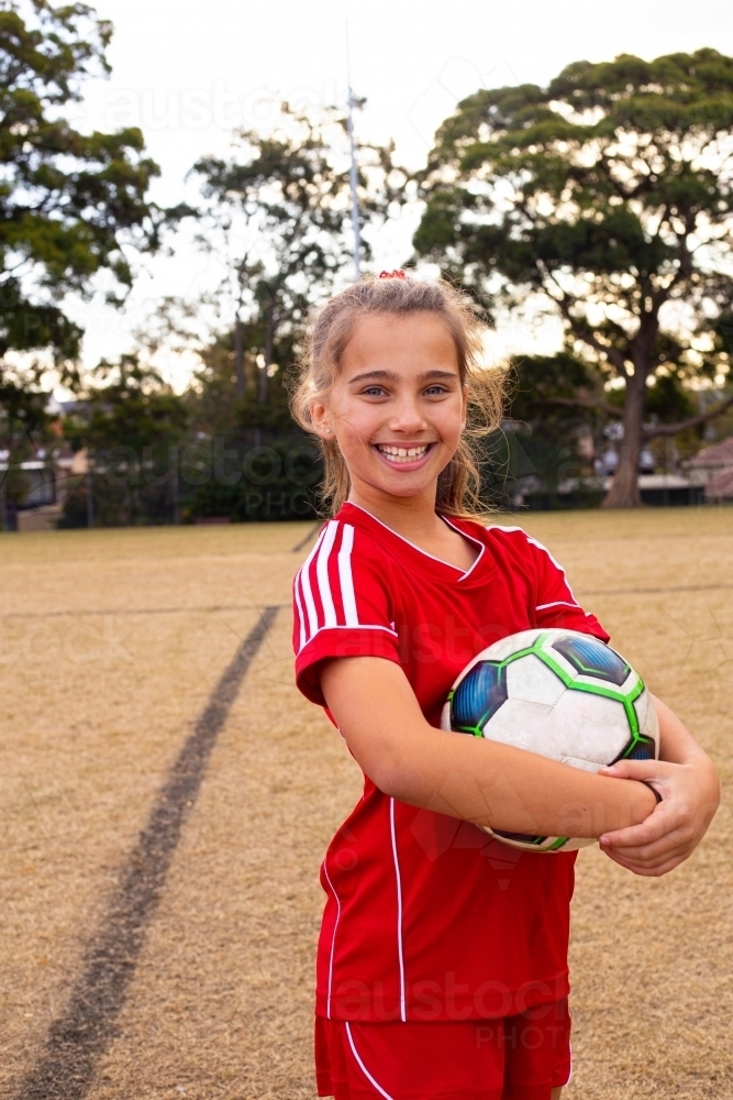 Image of Girl proudly holding a soccer ball and smiling looking at the ...