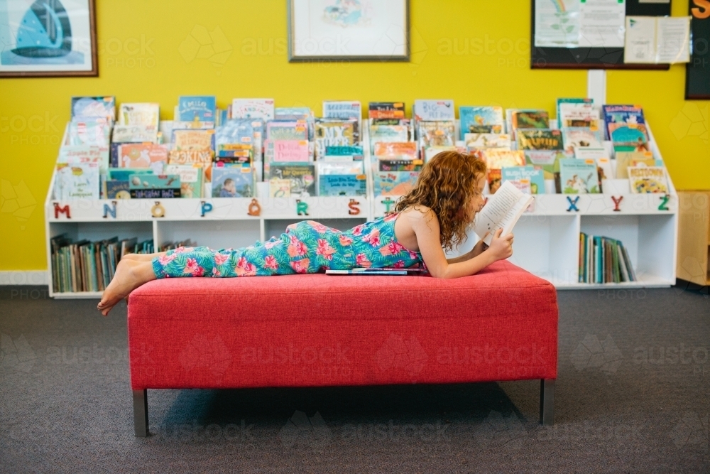Image of Girl reading a book at the Library - Austockphoto