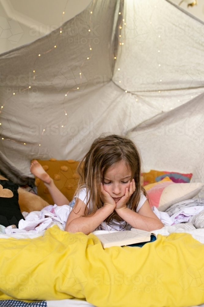 Image of Girl reading a book in the tent - Austockphoto