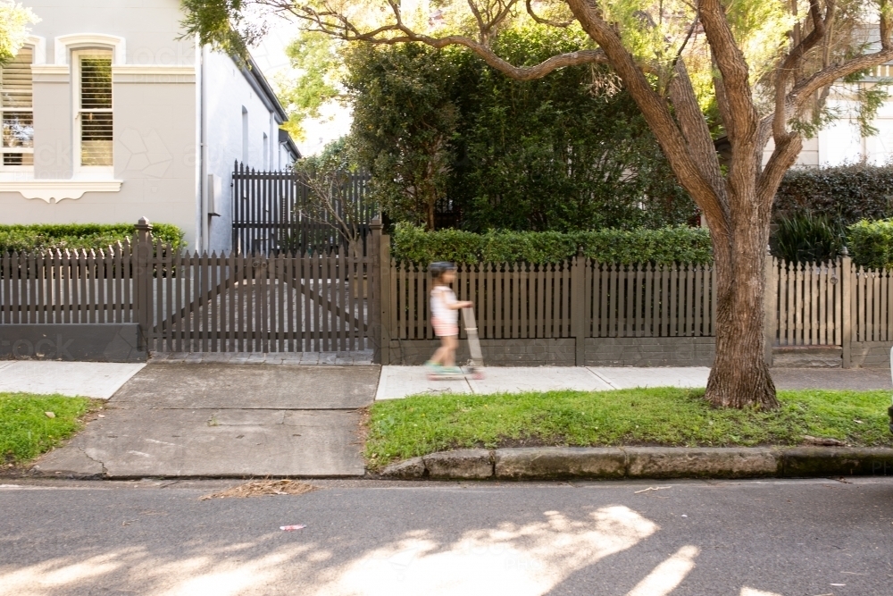 Image of girl riding on a scooter with helmet on the sidewalk with a ...