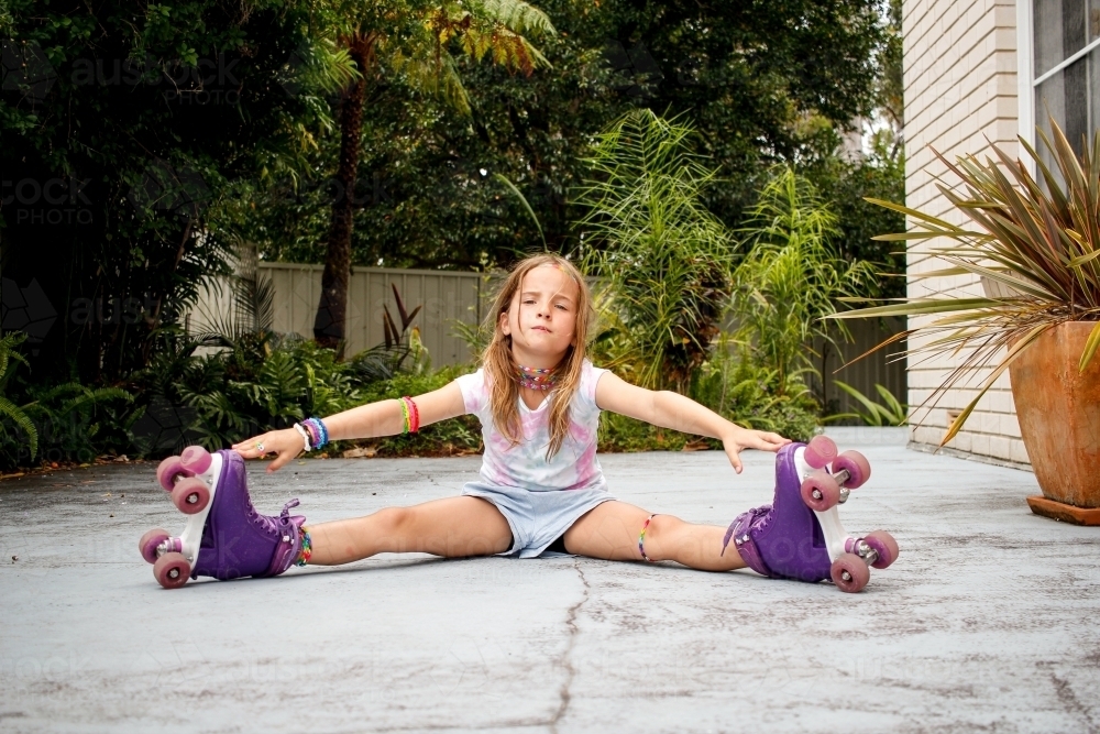 Image of Girl sitting down on the ground with her roller skates on ...