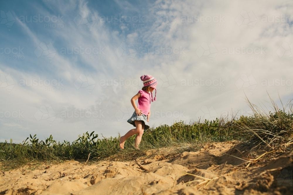 Image of Girl walking along the sand at the beach - Austockphoto