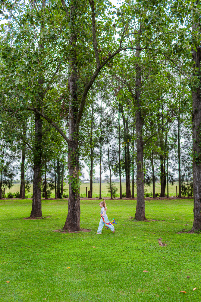 Image of Girl with rainbow streamers running around outside in country ...