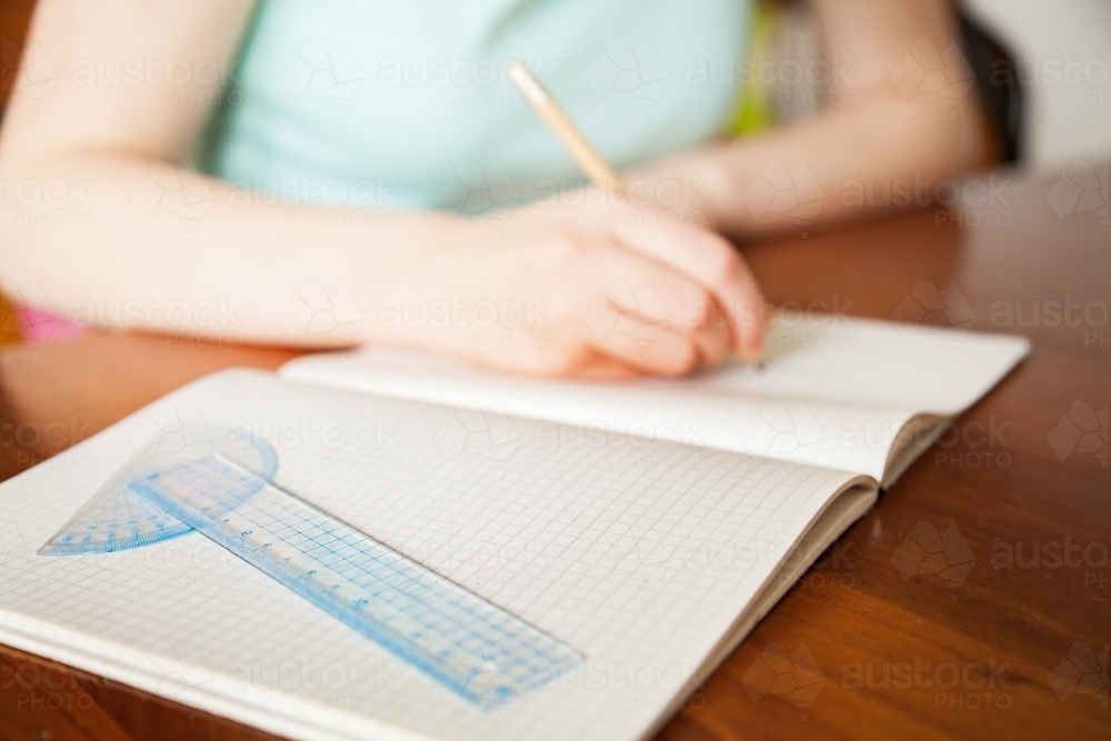 Image of Girl writing in blank graph paper school book - Austockphoto
