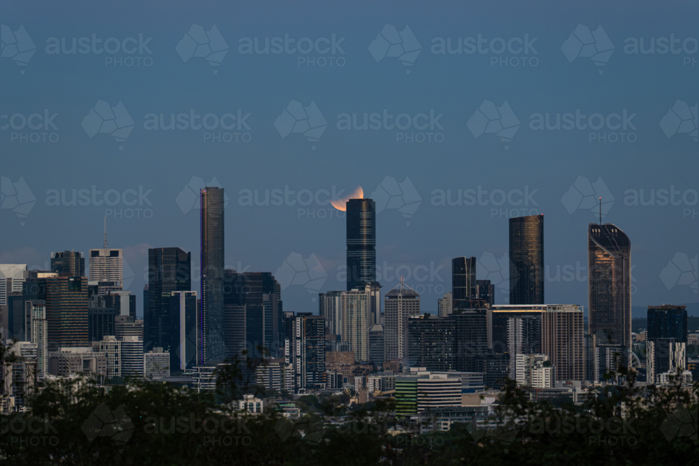 Image of Glowing eclipse of the full moon shining over city skyline ...