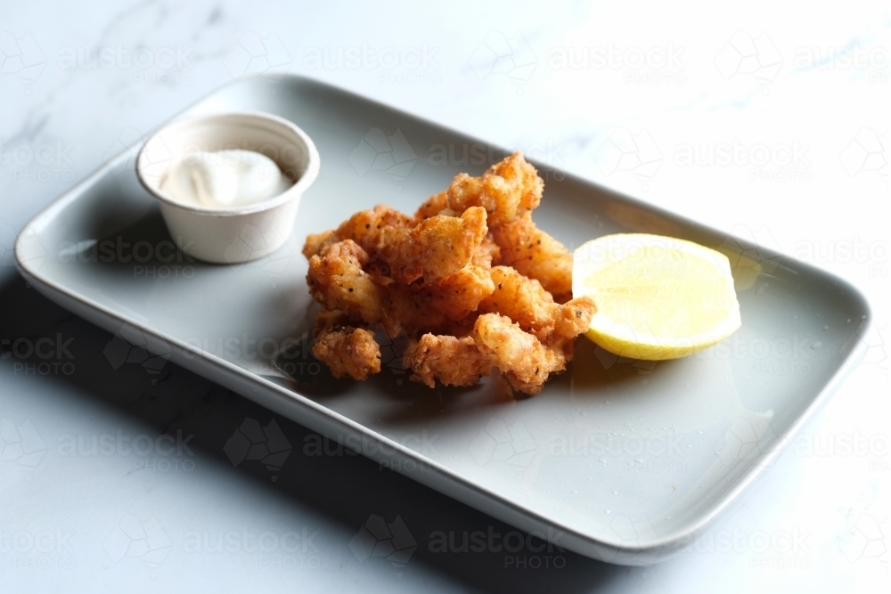 Image of Golden fried fillets with white dipping sauce and a slice of ...