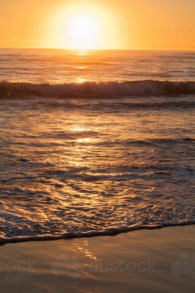 Image of Golden sun rising over ocean waves - Austockphoto