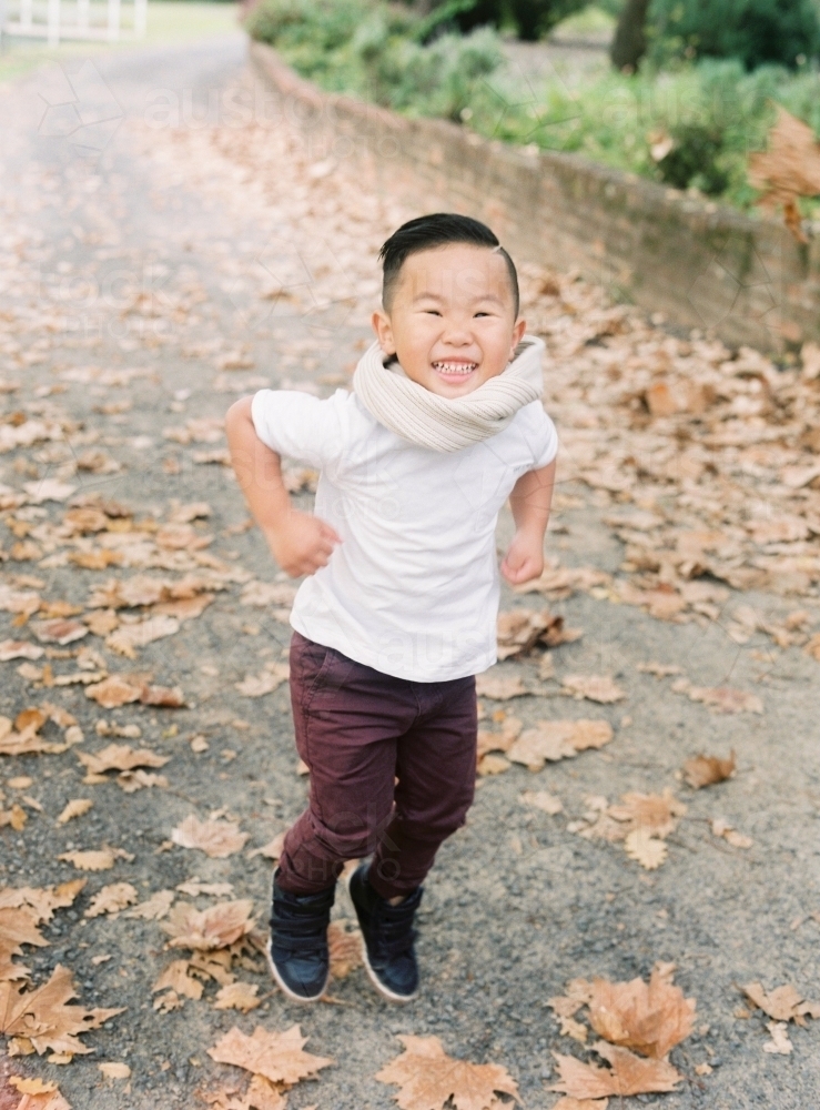Image of Gorgeous, young boy jumping outside with huge smile - Austockphoto