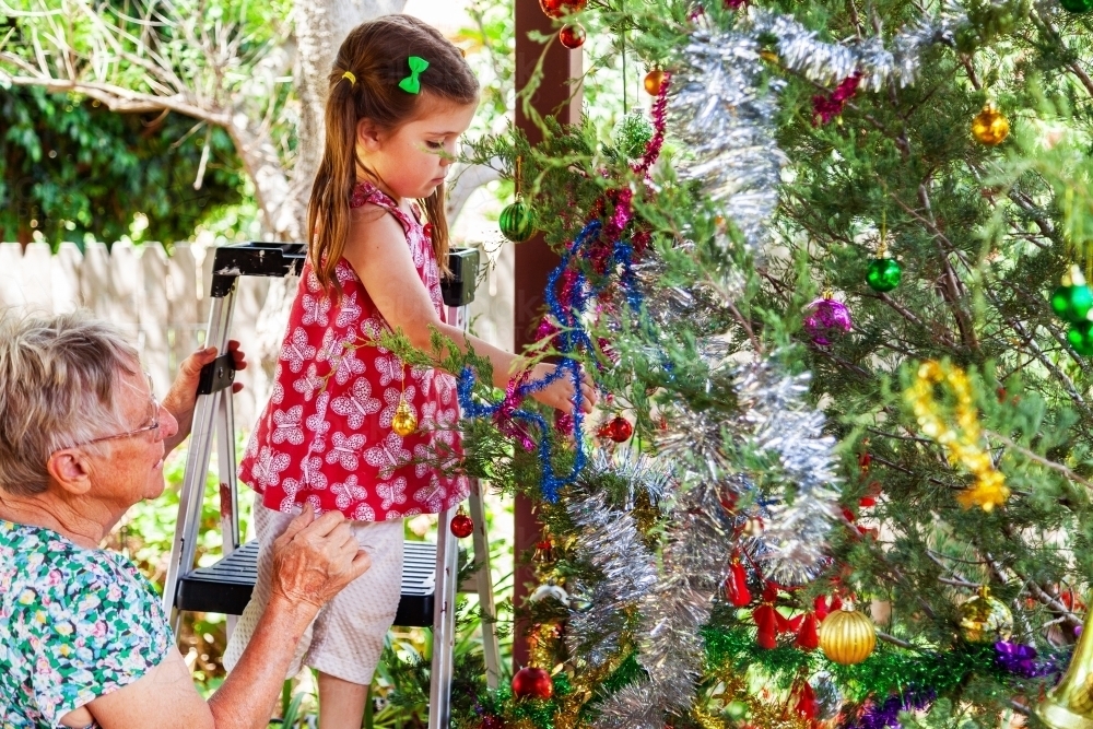 Image of Grandchild with grandmother hanging decorations on Christmas ...