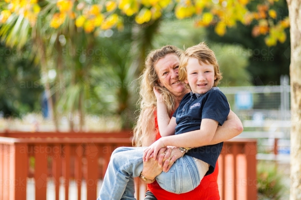 Image of Grandmother carrying grandson while smiling at the camera ...