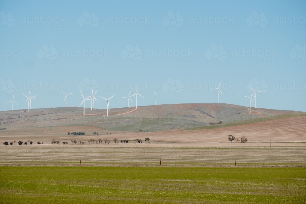 Image of Grassland with wind turbines on hilltop - Austockphoto