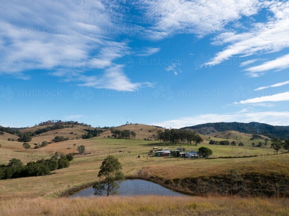 Image of Grazing country with a farm dam, house and hills - Austockphoto