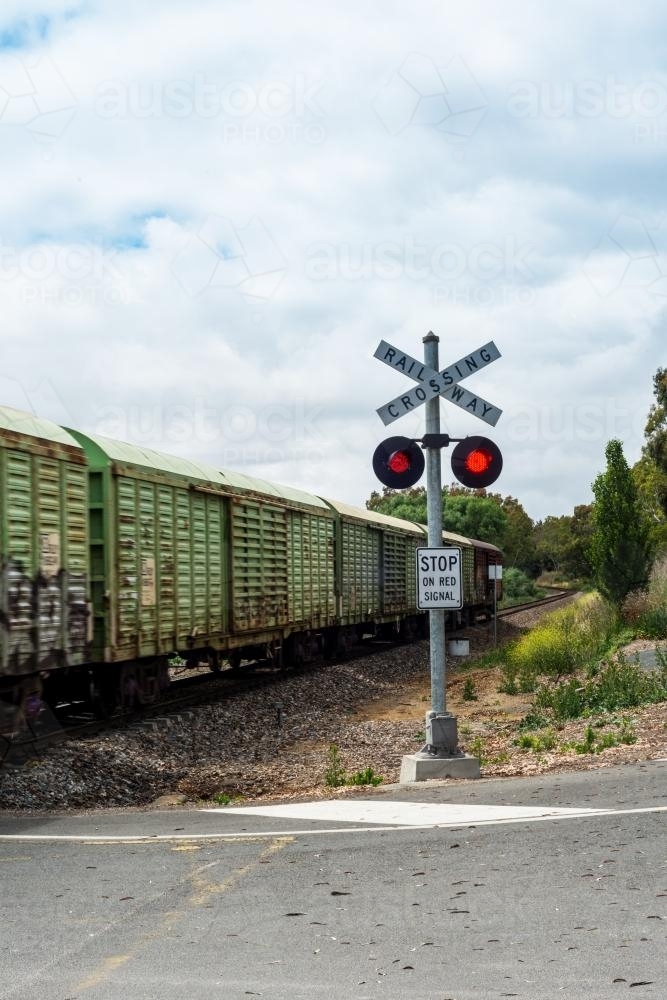 Image of Green freight train going through level crossing - Austockphoto