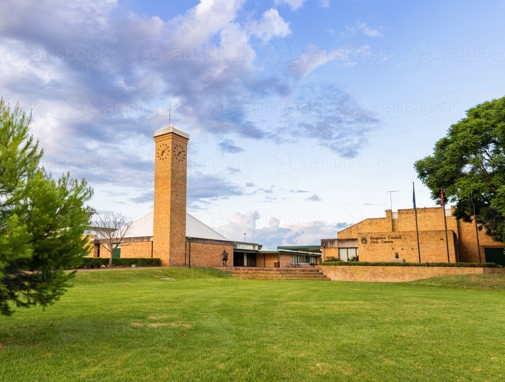 Image of Green lawn to brick buildings and clock tower in town at dusk ...