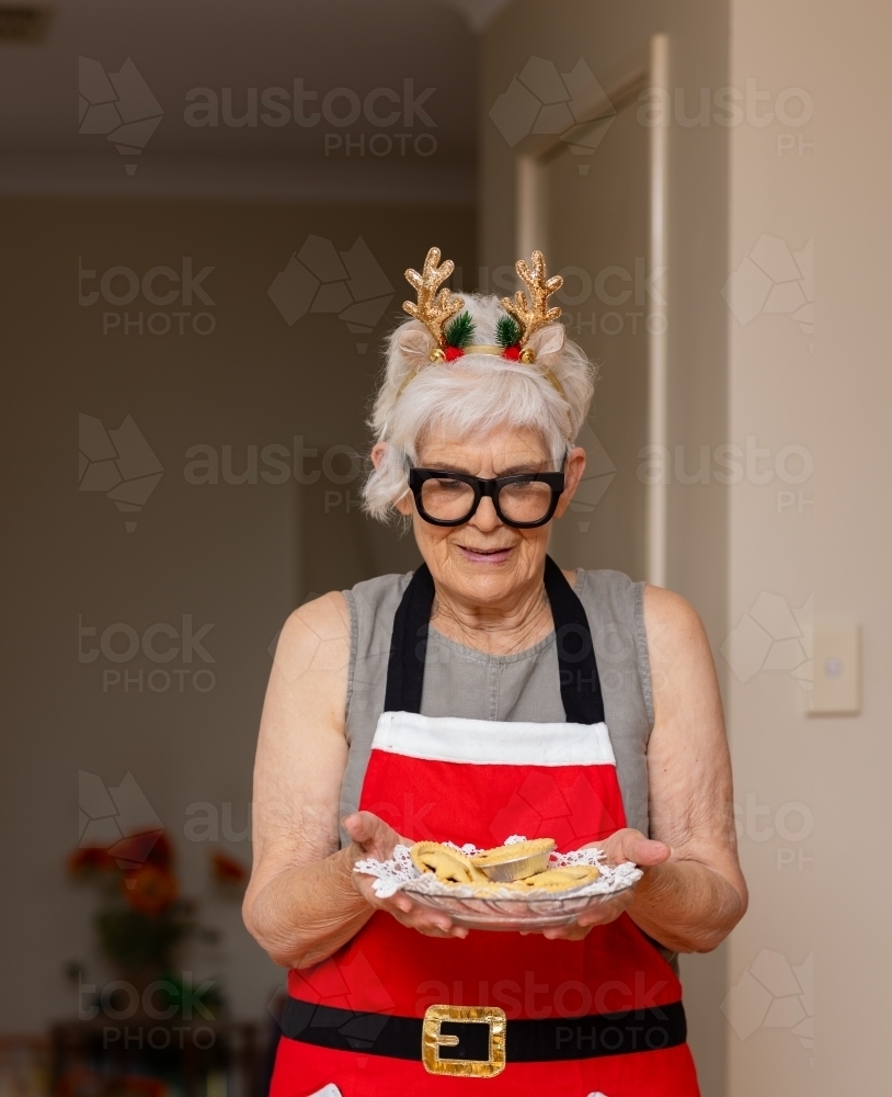 Image of grey-haired lady carefully carrying plate of fruit mince pies ...