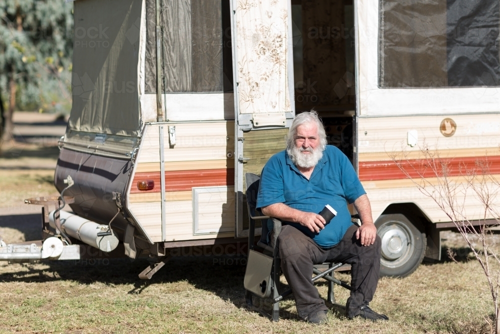 Image of Grey haired man sitting in front of pop-up caravan - Austockphoto
