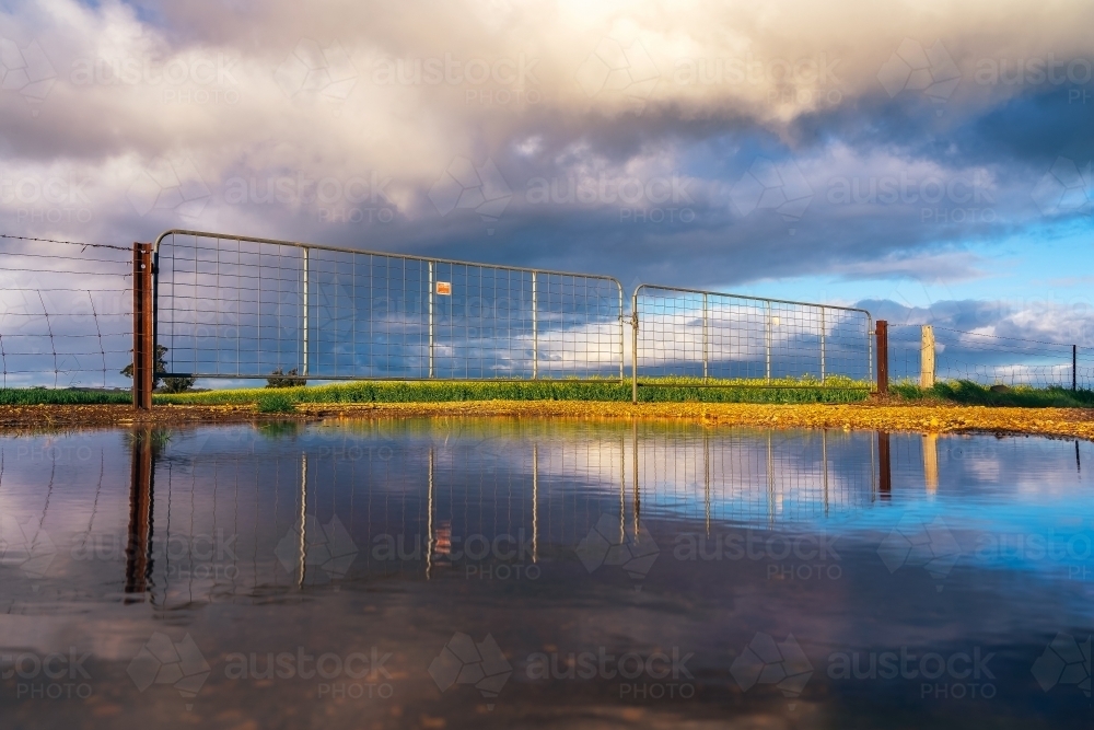Image of Ground level view of a pool of water in front of a farm gate ...