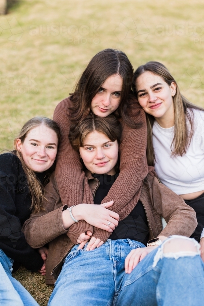 Image of Group of four girls snuggled together sitting on grass smiling ...