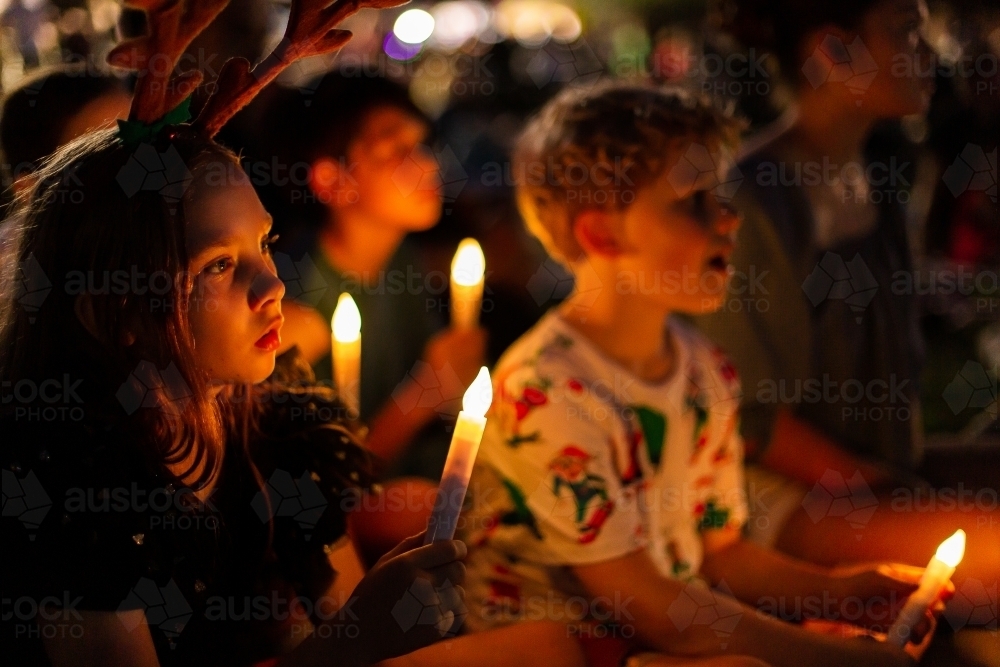 Image of group of kids at carols by candlelight at night - Austockphoto
