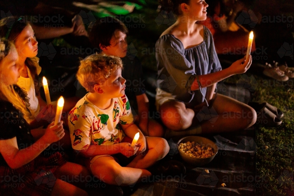 Image of group of kids sharing a picnic blanket and popcorn at carols ...