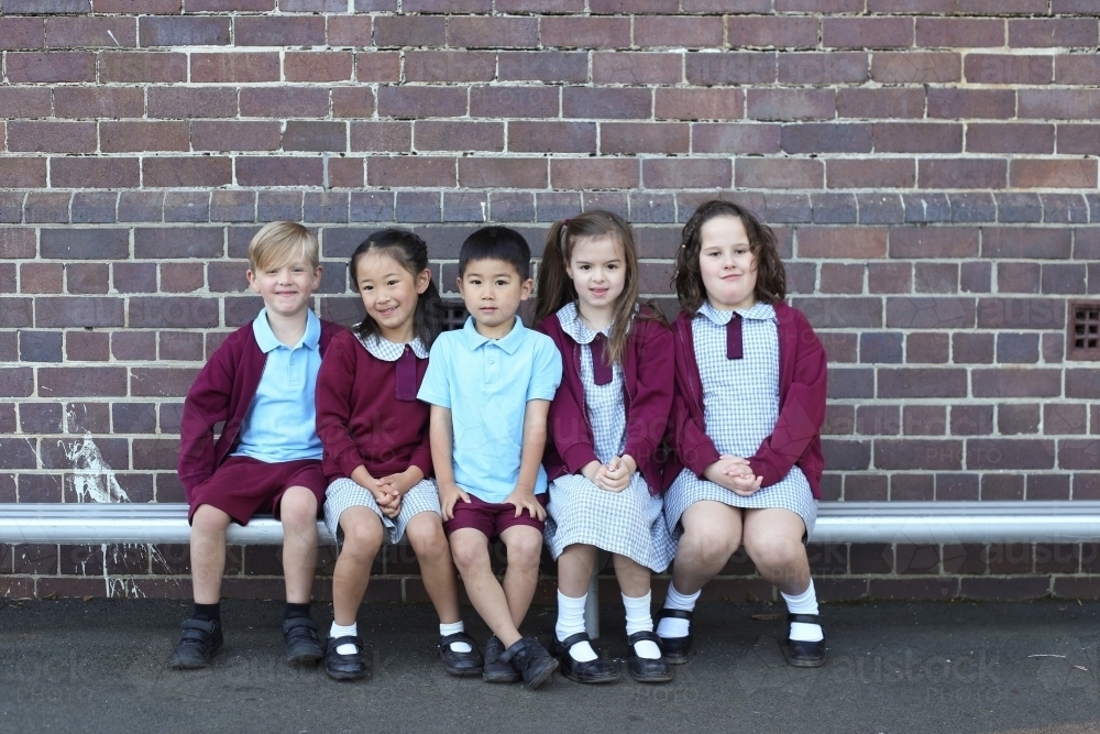 Image of Group of kids sitting together on a school bench outside ...