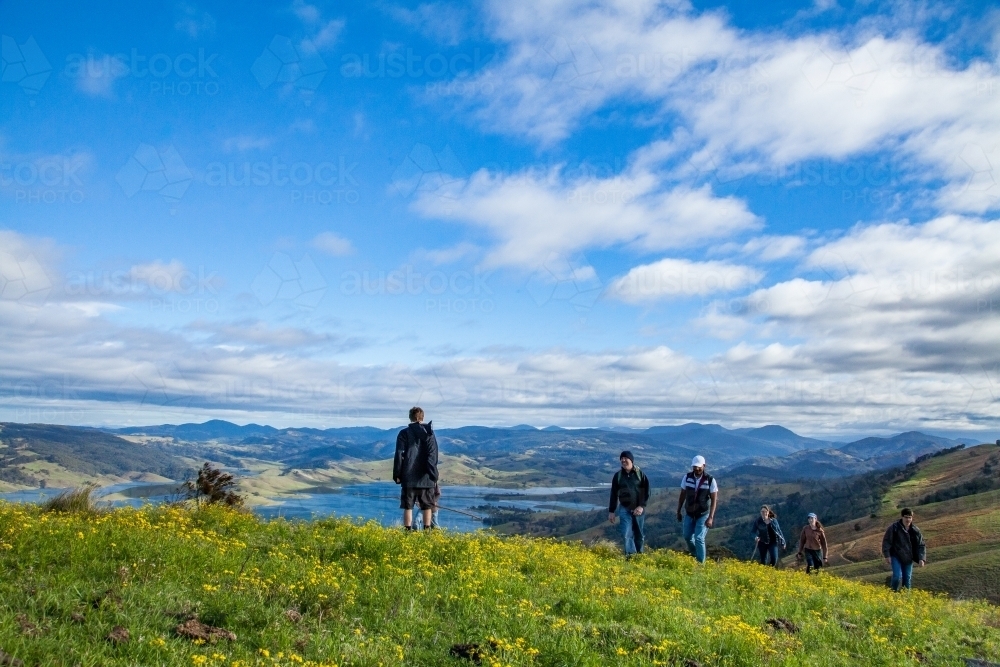 Image of Group of people walking up to the top of a hill - Austockphoto
