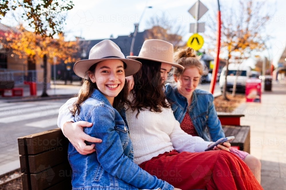 Image of Group of three teenaged friends sitting together in urban area ...