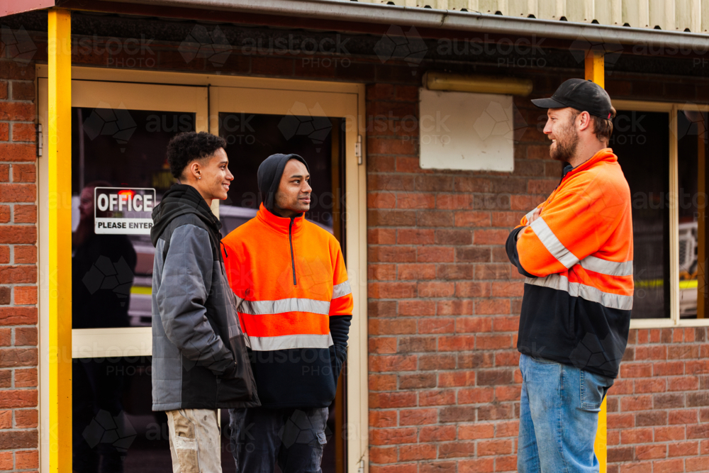 Image of Group of workmen mechanics chatting together outside office at ...