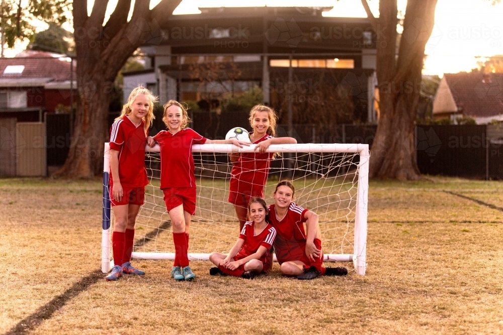 Image of Group portrait of a tween girls football team leaning against ...