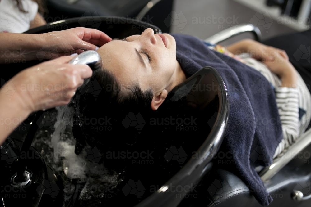 Image of Hairdresser washing a woman's hair at a salon - Austockphoto
