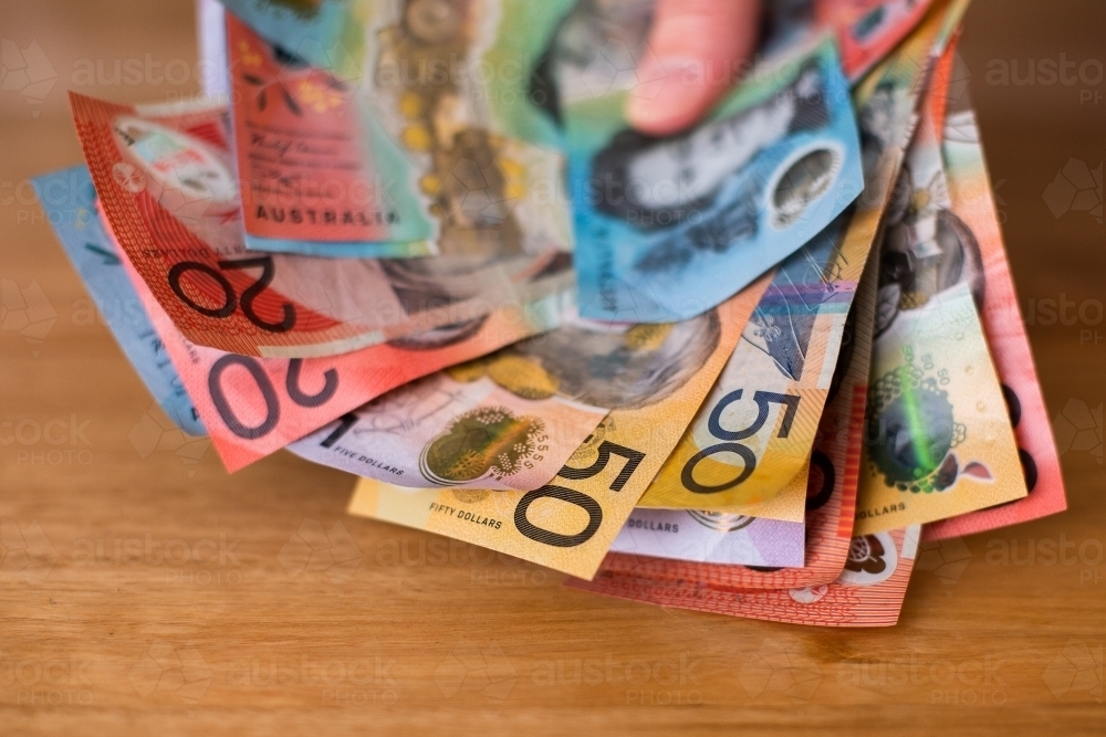 Image of hand holding assorted cash money in a fan - Austockphoto