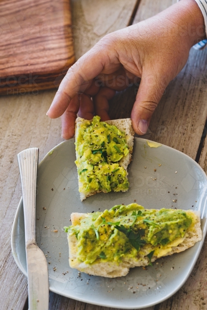 Image of hand on avo toast - Austockphoto