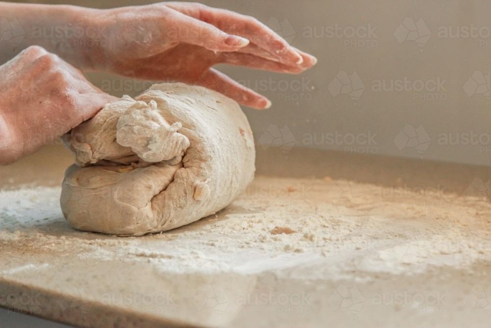 Image of Hands kneading dough on the kitchen bench - Austockphoto