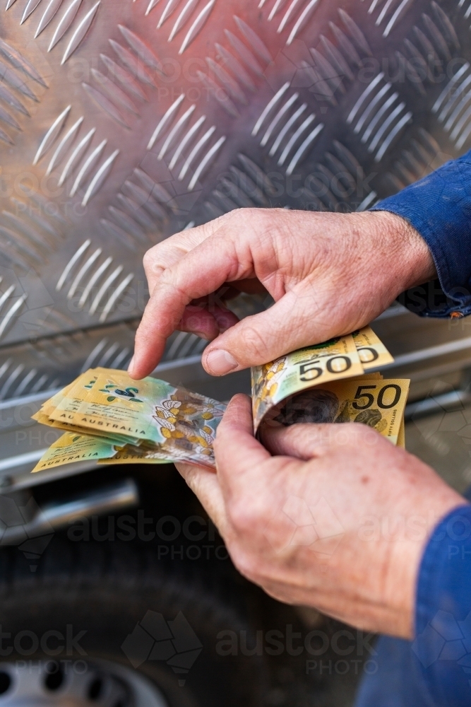 Image of Hands of a handyman counting cash beside tradie ute - Austockphoto