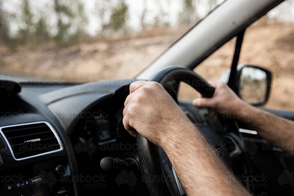 Image of hands on a steering wheel on a highway drive - Austockphoto