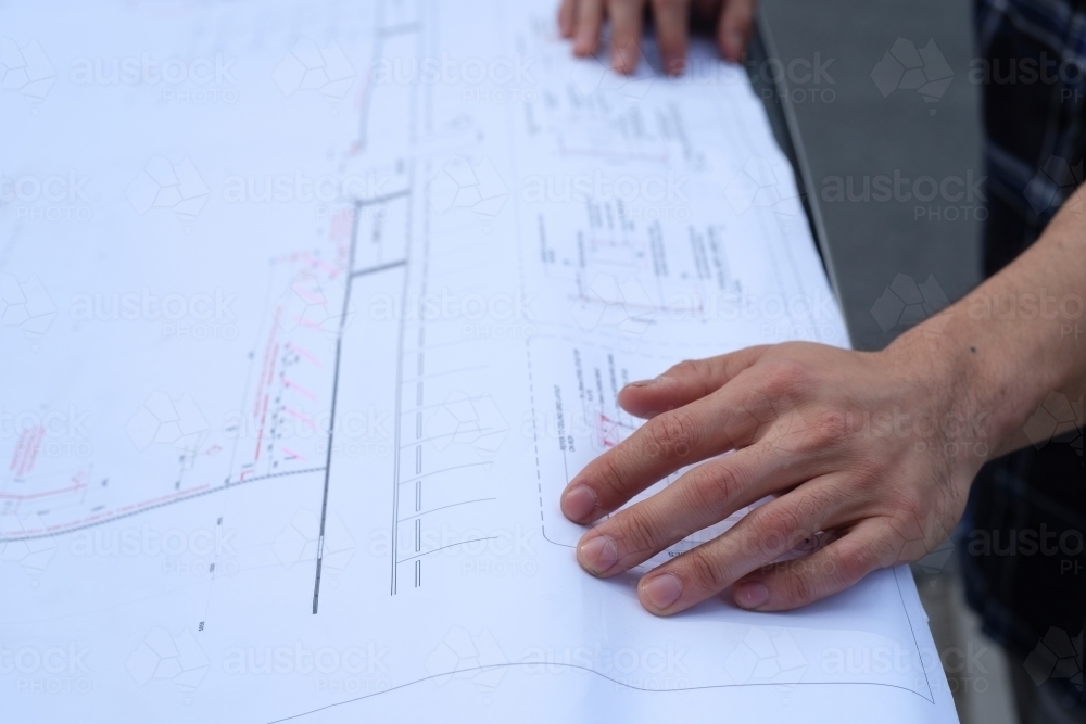 Image of Hands running over urban planning paper - Austockphoto