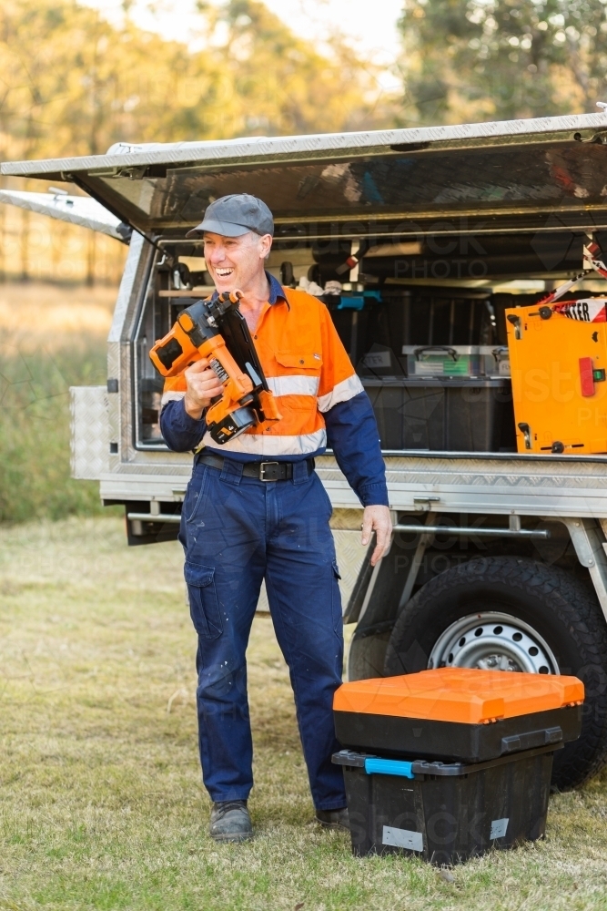 Image of Handyman with nail gun power tool beside tradie ute - Austockphoto