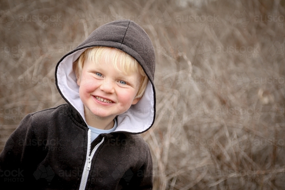 Image of Happy 3 year old boy in nature surrounded by dry wild grasses ...