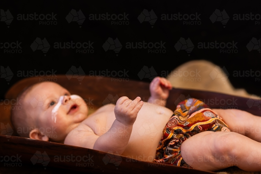 Image of Happy Aboriginal baby boy lying on possum skin in coolamon ...