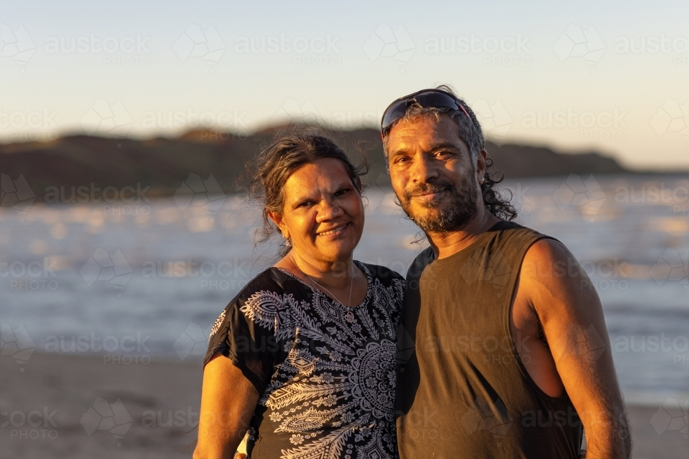 Image of happy aboriginal couple standing at the beach in golden light ...
