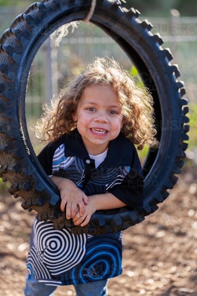 Image of Happy aboriginal girl on tyre swing in backyard - Austockphoto
