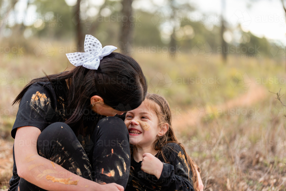 Image of Happy aboriginal sisters sitting together smiling in bushland ...