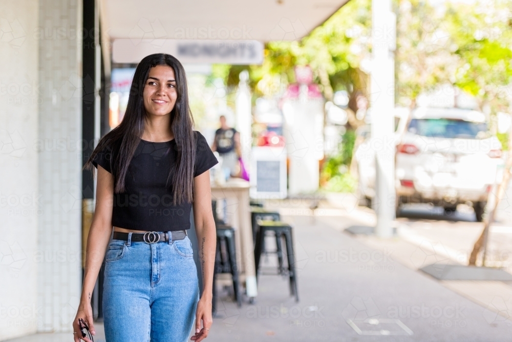 Image of happy aboriginal woman walking in an urban setting - Austockphoto